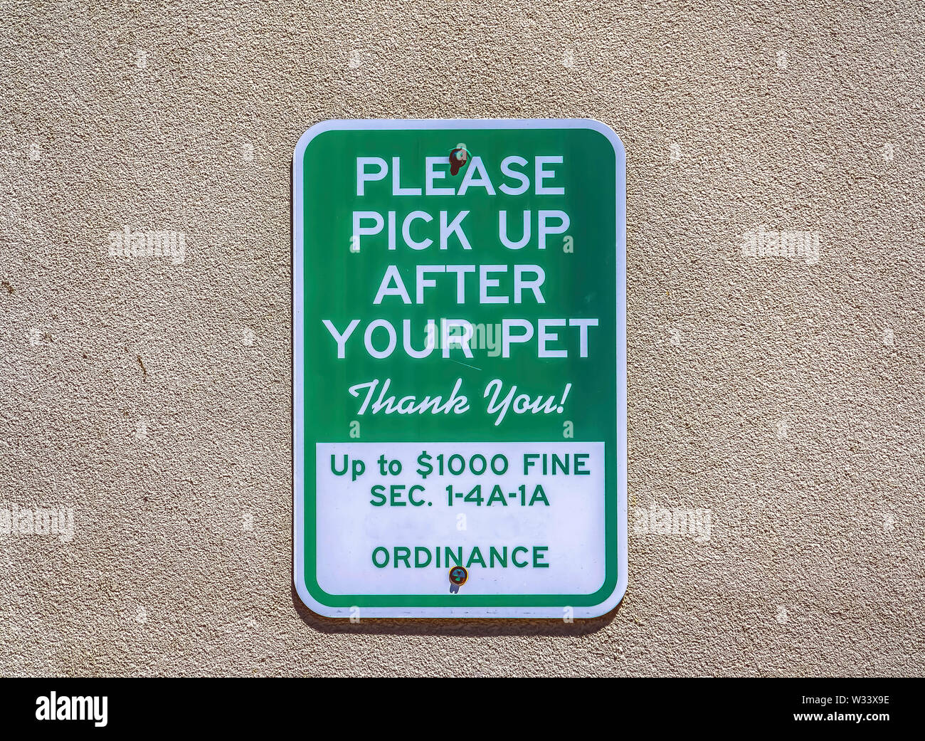 Sign that reads Please Pick Up After Your Pet against a concrete wall ...