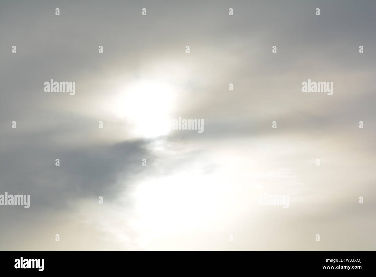 Hazy diffused sun trying to shine through thin sheet of cloud, makes ...