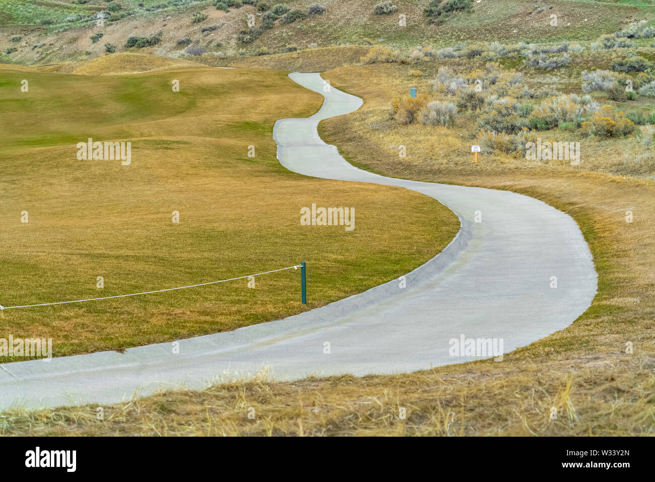 Narrow road paved with concrete and winding through the slope of a hill ...