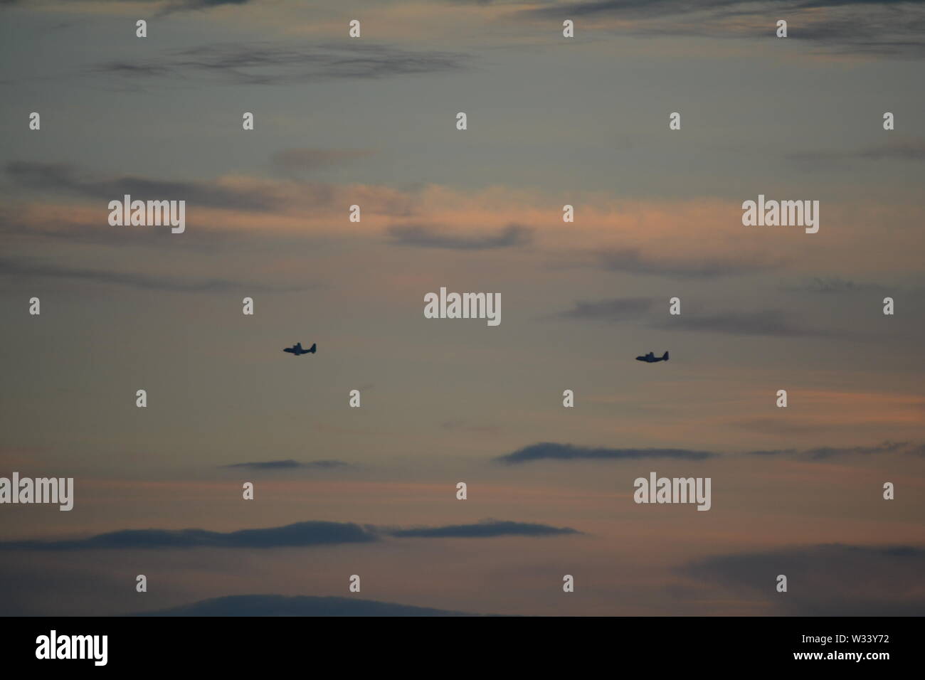 evening sunset, clouds with C130 hercules transport aircraft flying in ...