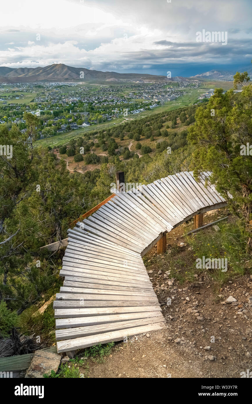 Close up of a wooden bridge amid trees and curving over the slope in ...