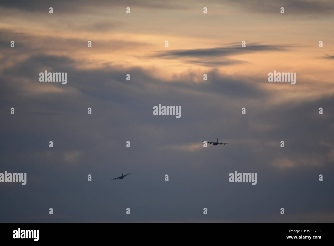 evening sunset, clouds with C130 hercules transport aircraft flying in ...