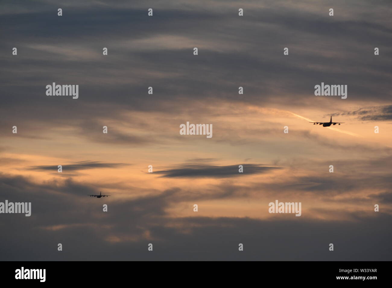 evening sunset, clouds with C130 hercules transport aircraft flying in ...