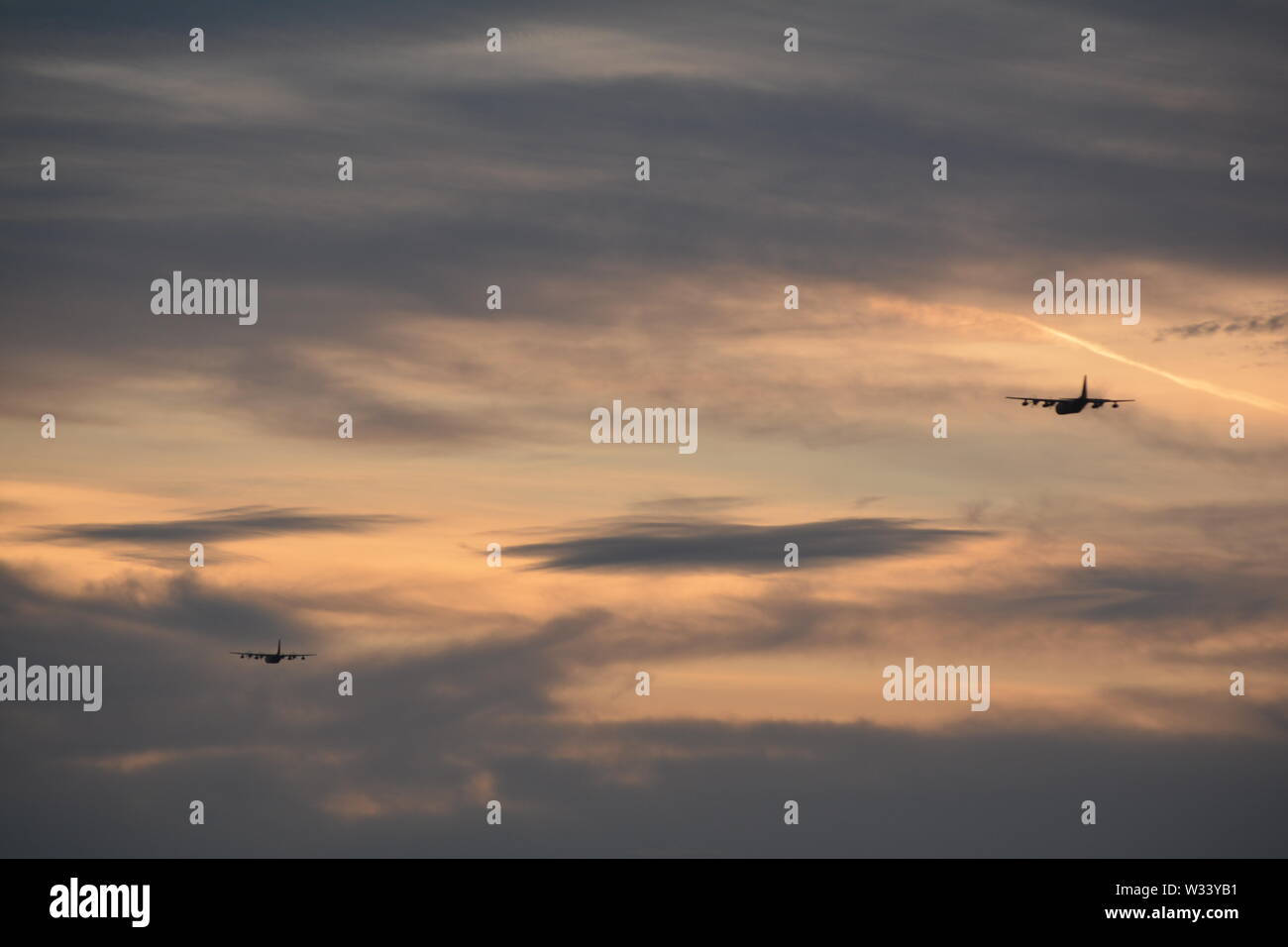 evening sunset, clouds with C130 hercules transport aircraft flying in ...