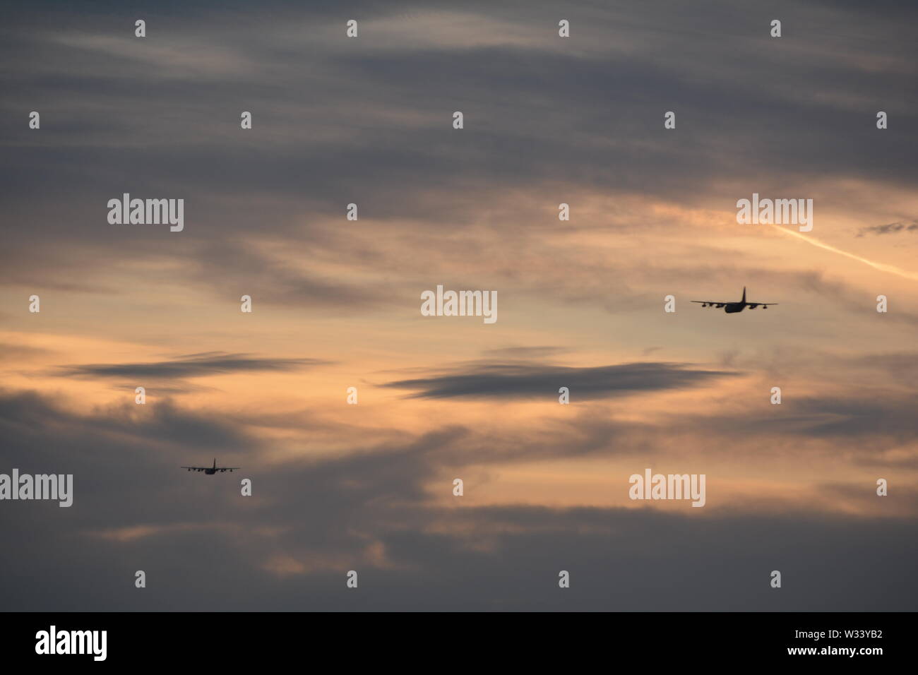 evening sunset, clouds with C130 hercules transport aircraft flying in ...