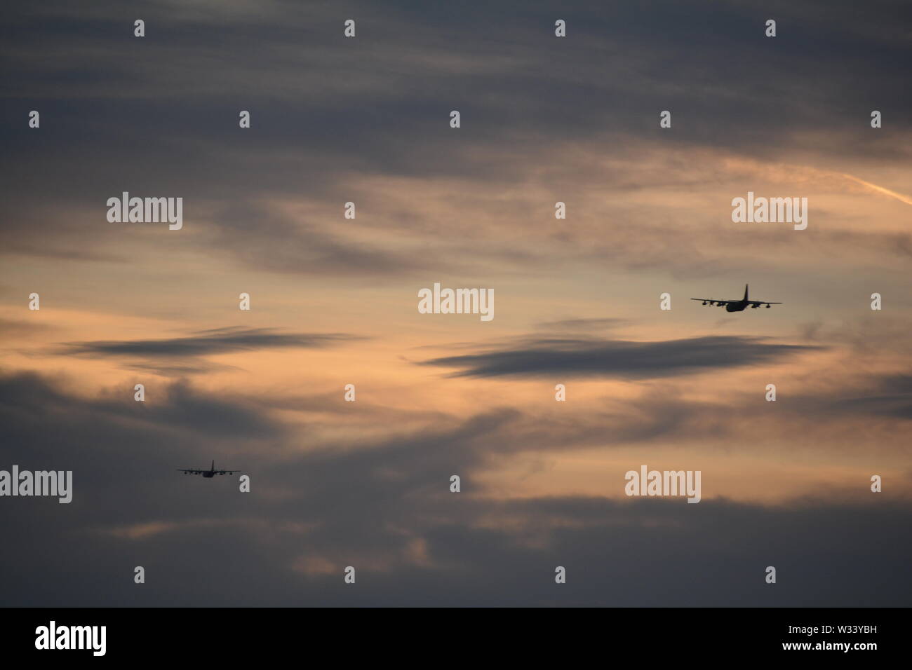 evening sunset, clouds with C130 hercules transport aircraft flying in ...