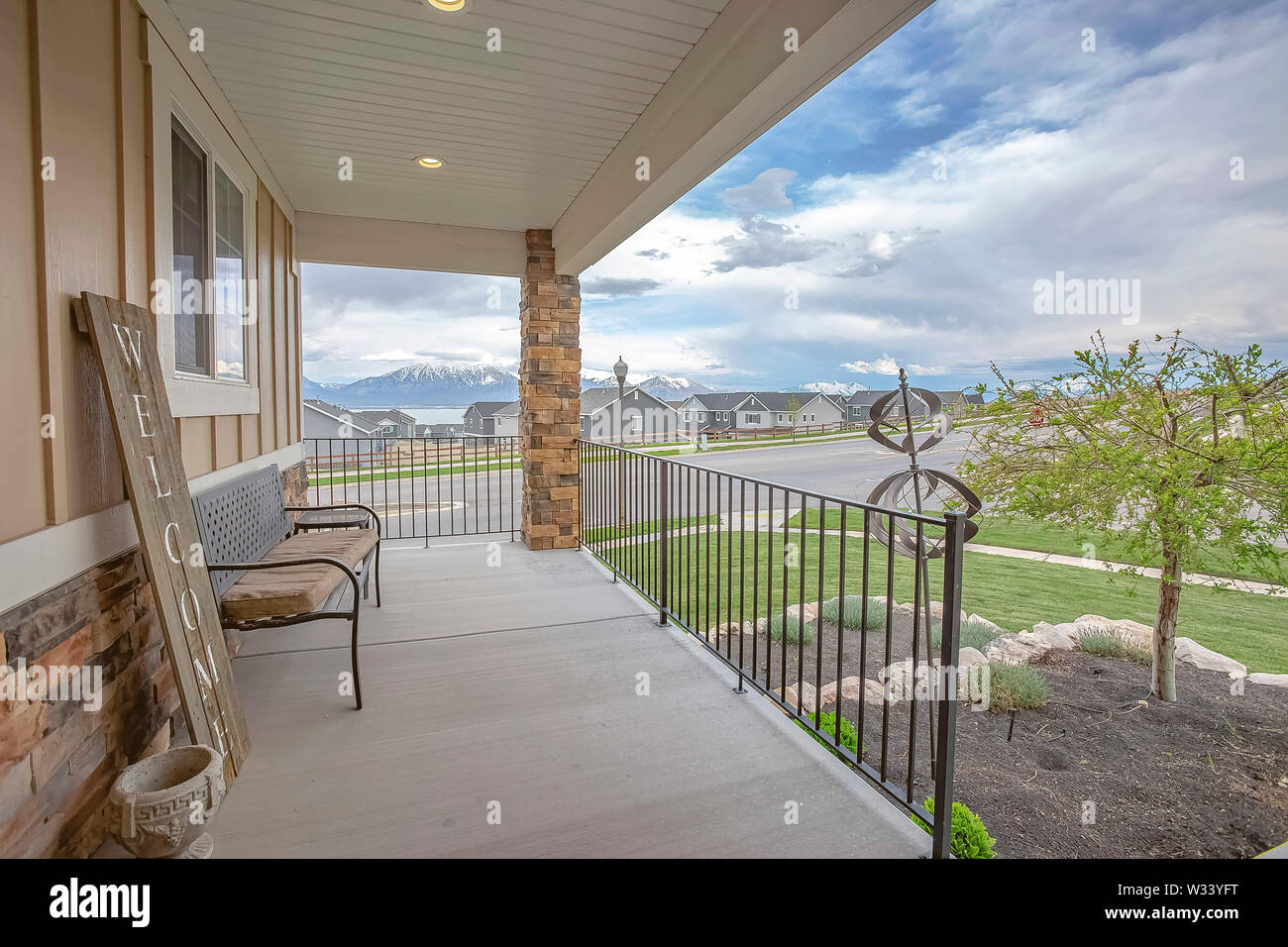 Porch overlooking yard road homes lake and mountain under cloudy blue ...