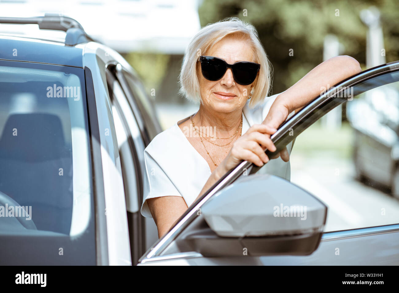 Portrait of a beautiful senior business woman standing near the car ...