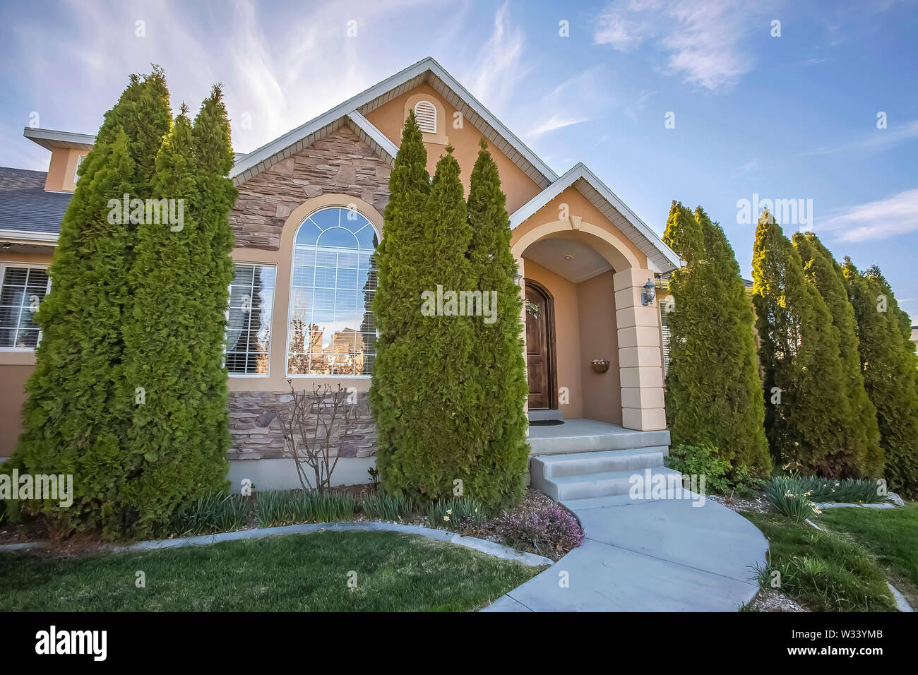 Home exterior with stone wall and pathway leading to the arched entry ...