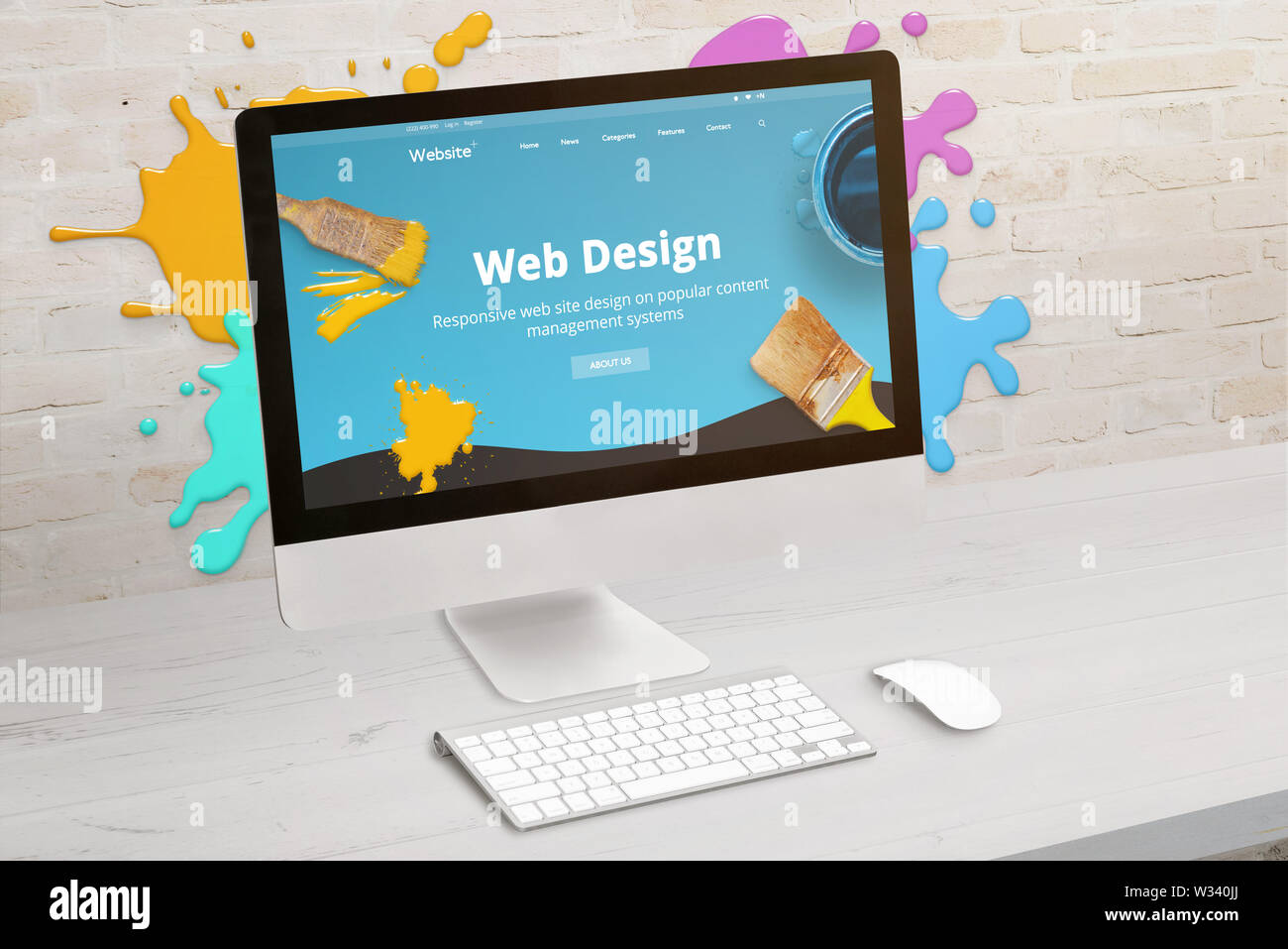 Concept of web design studio with coimputer display and color drops on brick wall. Modern web ...