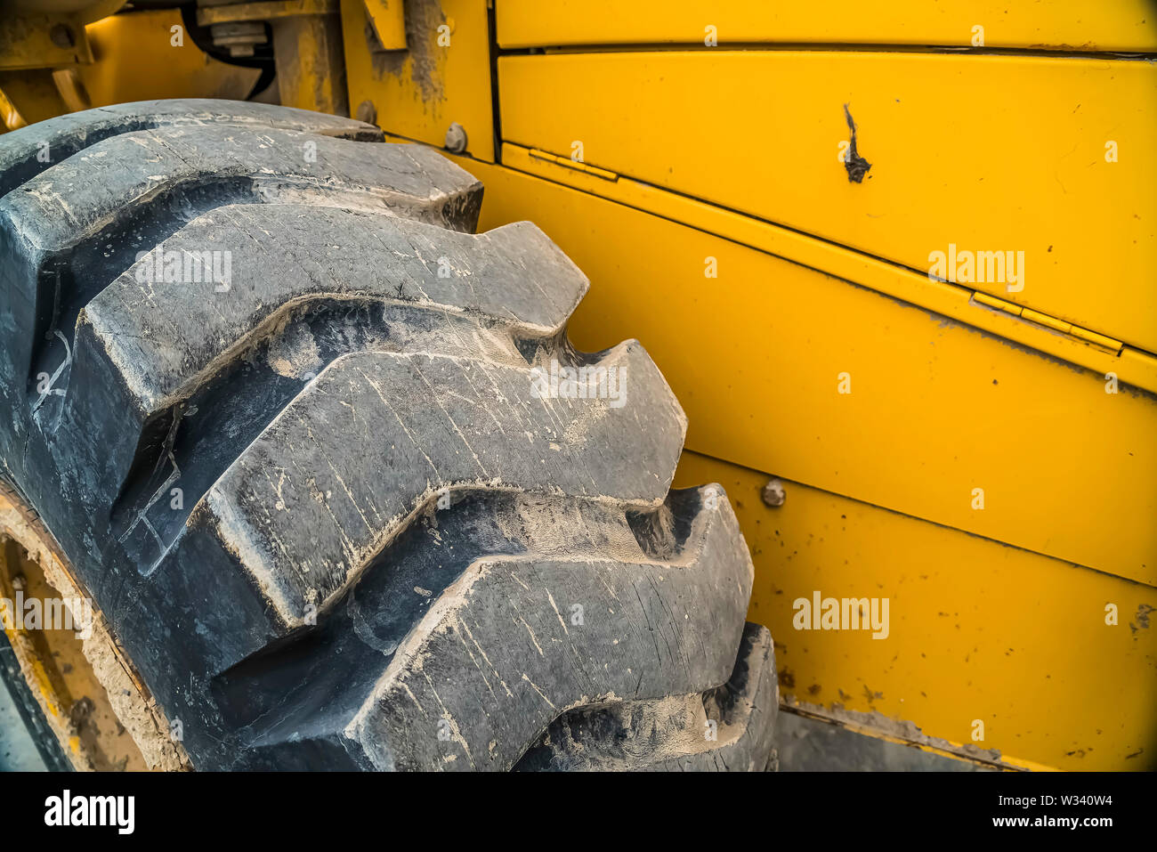 Close up of the black rubber tire of a construction vehicle with yellow ...
