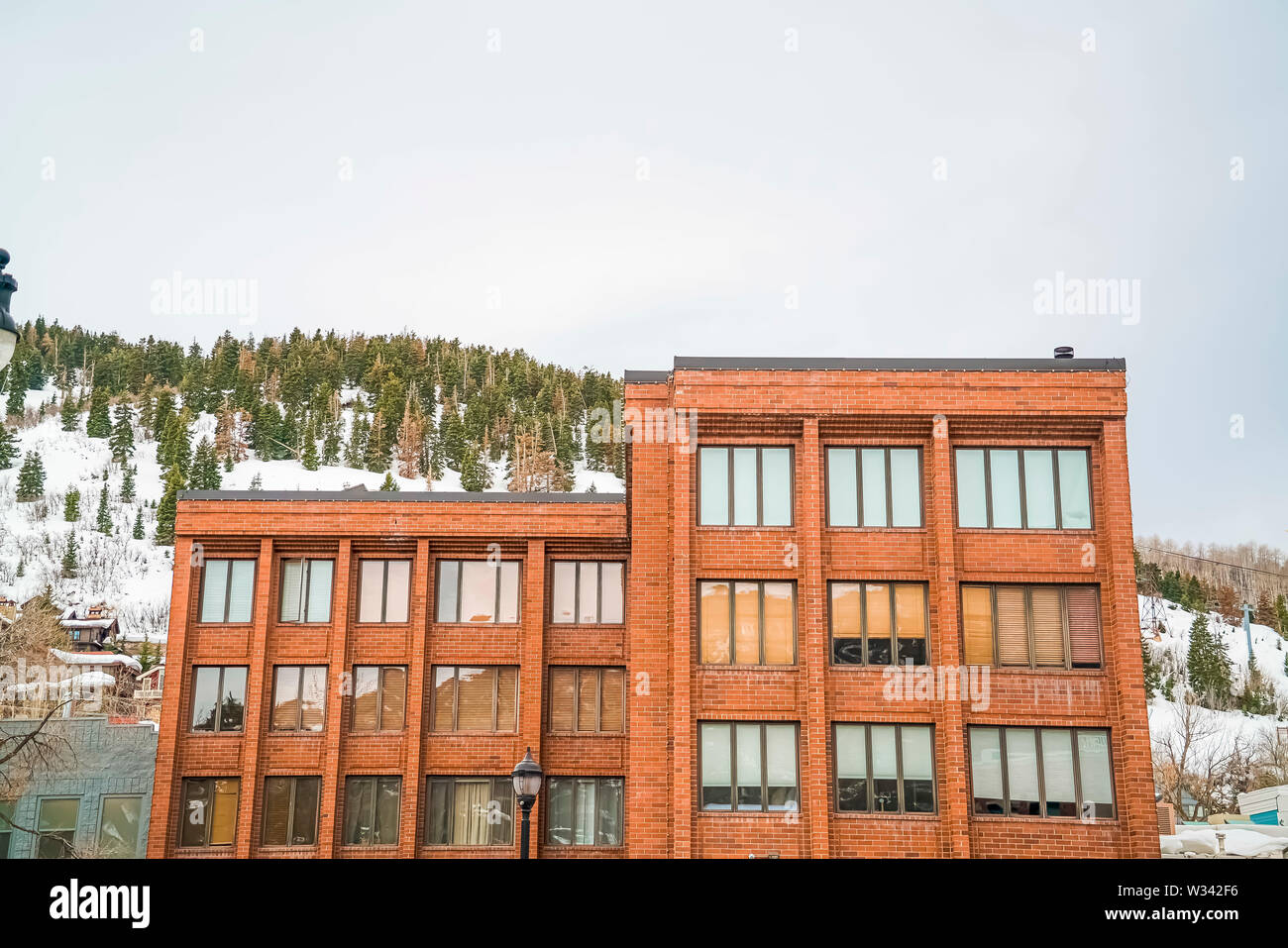 Exterior of a building with snowy mountain conifers and cloudy sky ...