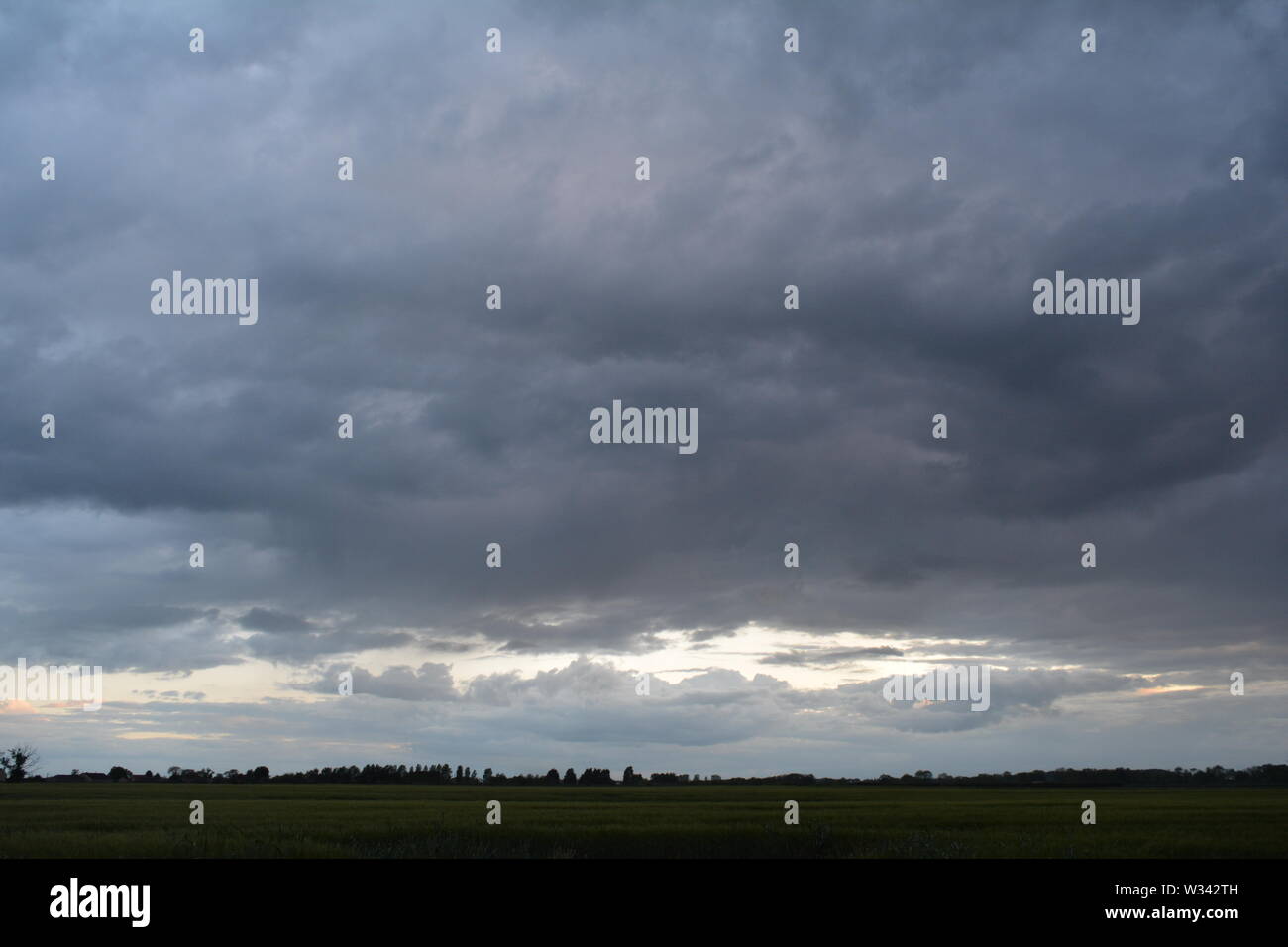 cloudy sweeping sky at dusk with hints of sun as it sets in Suffolk ...
