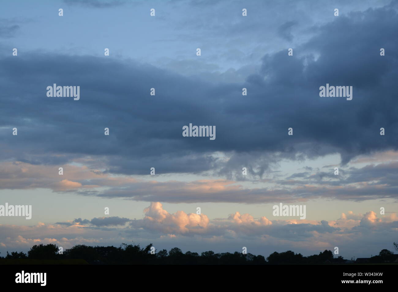 cloudy sweeping sky at dusk with hints of sun as it sets in Suffolk ...