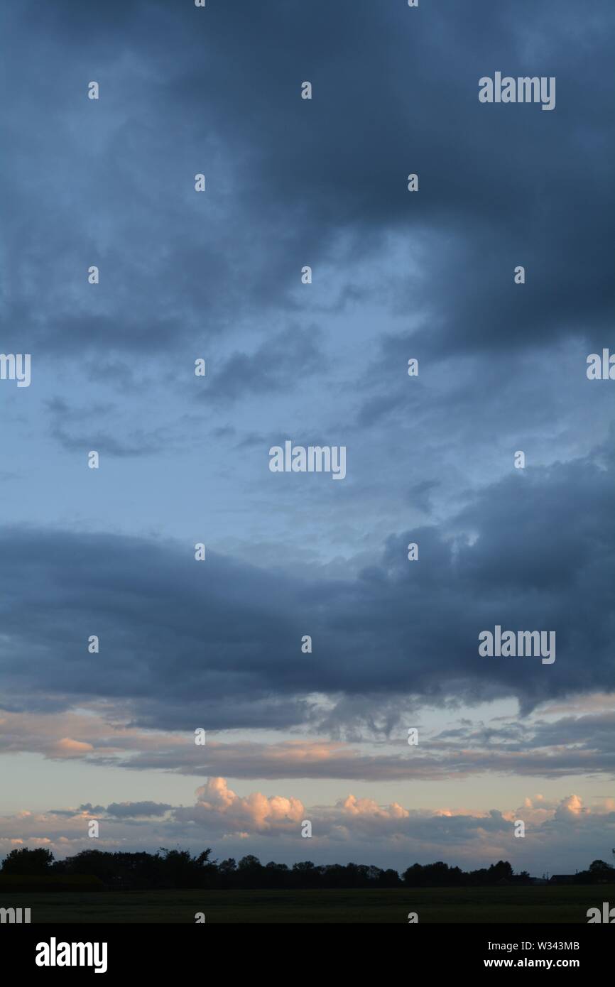 cloudy sweeping sky at dusk with hints of sun as it sets in Suffolk ...