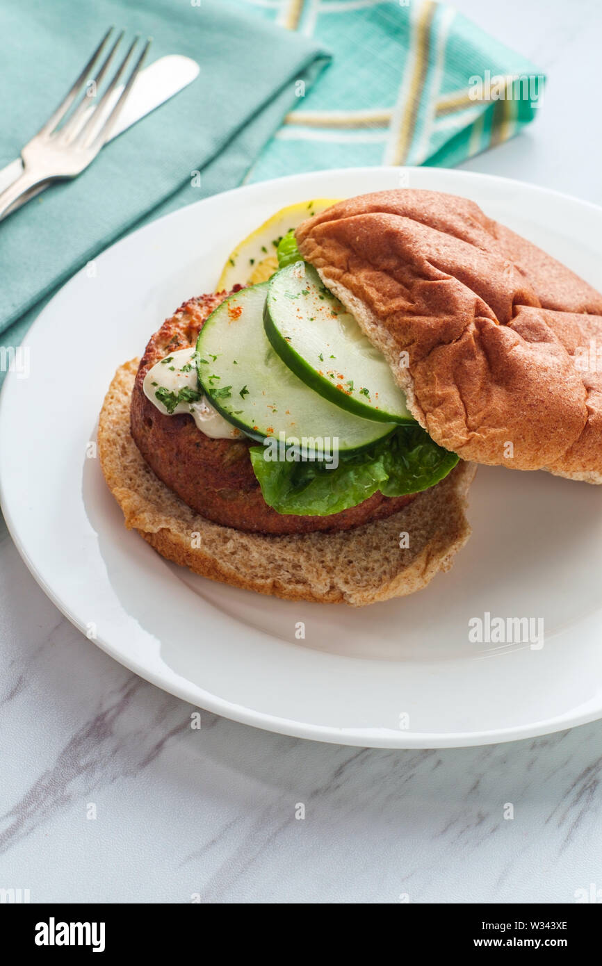 Seasoned fish cake sandwich on a whole wheat hamburger bun with creamy ...