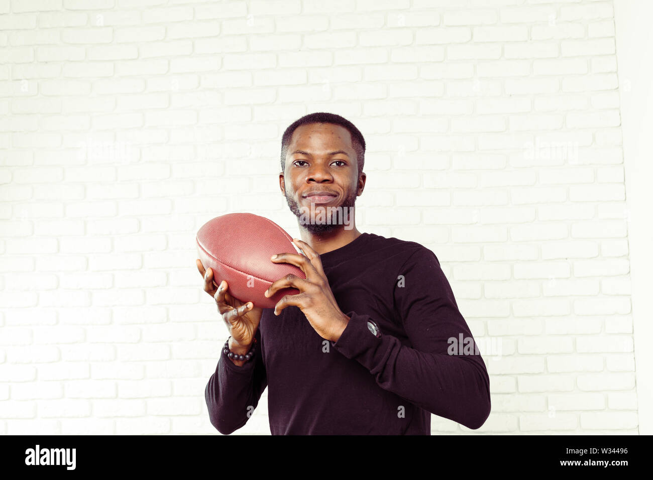 Friendly smiling black man holding a football Stock Photo - Alamy