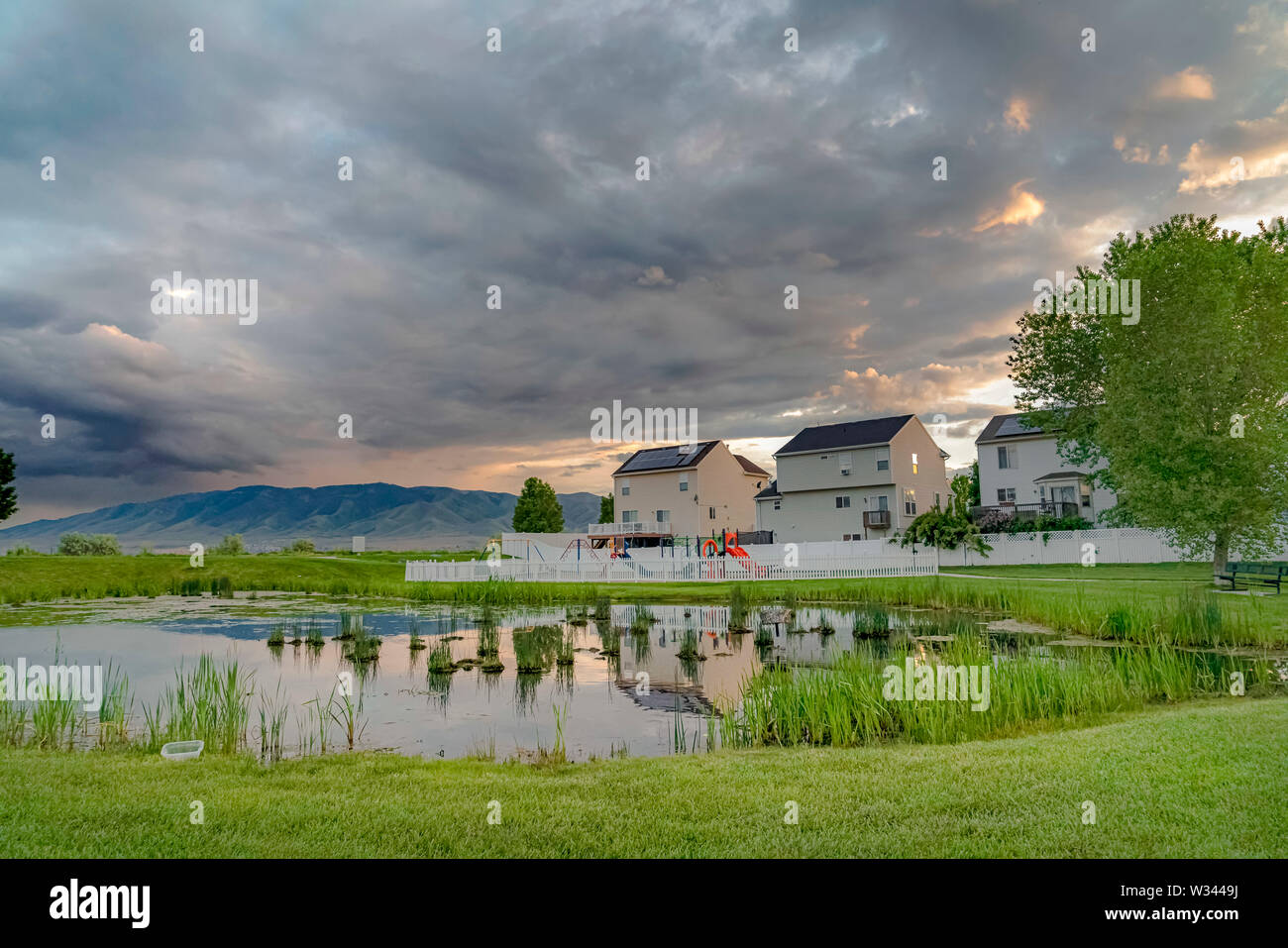 Shiny pond playground and multi storey homes surrounded by vast grassy ...