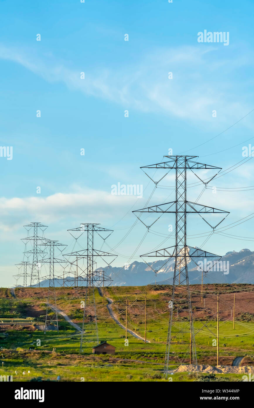 Towering power lines in the valley against snow capped mountain and ...