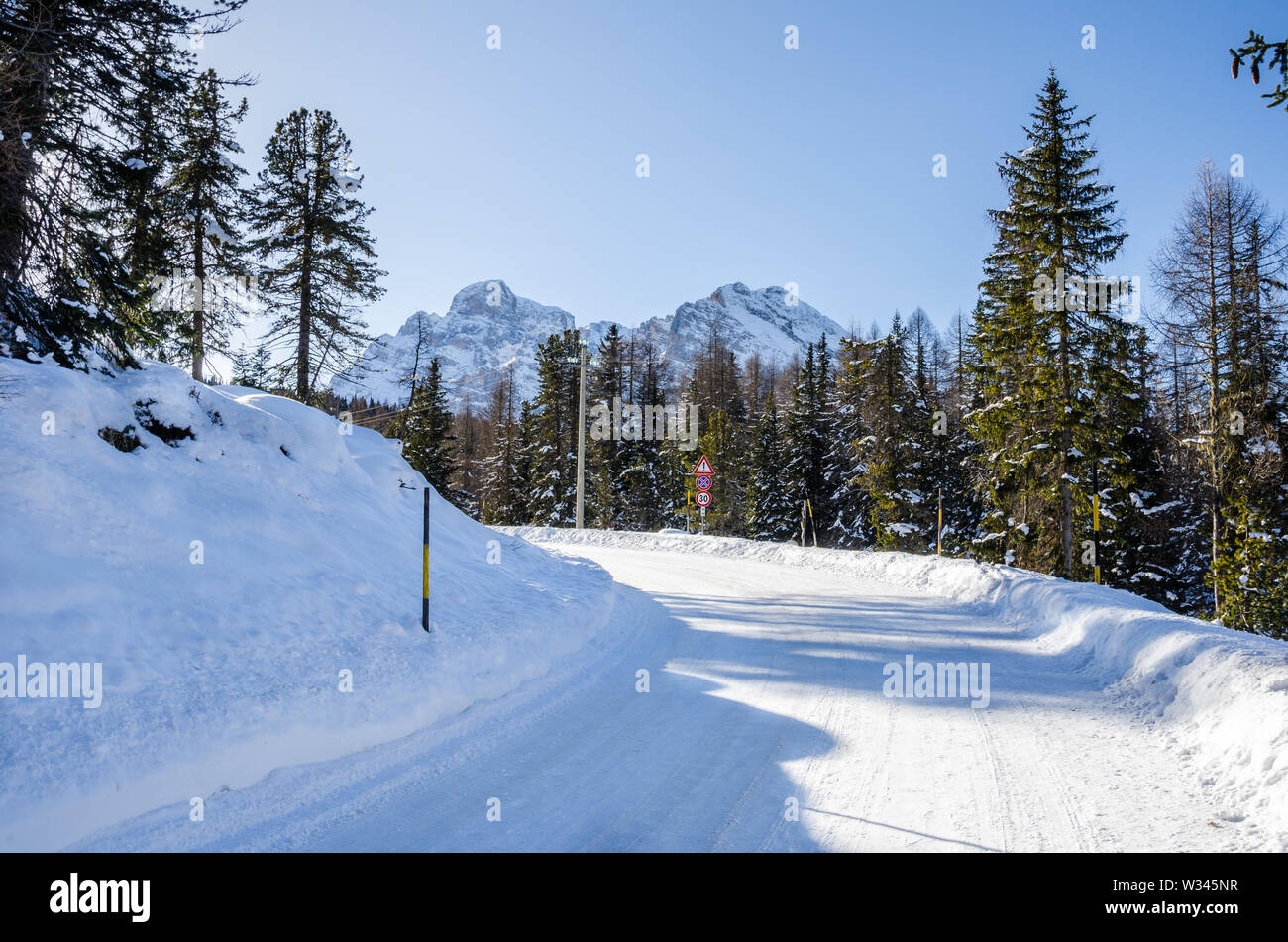 Empty snow covered mountain road in the Alps on a sunny winter day ...