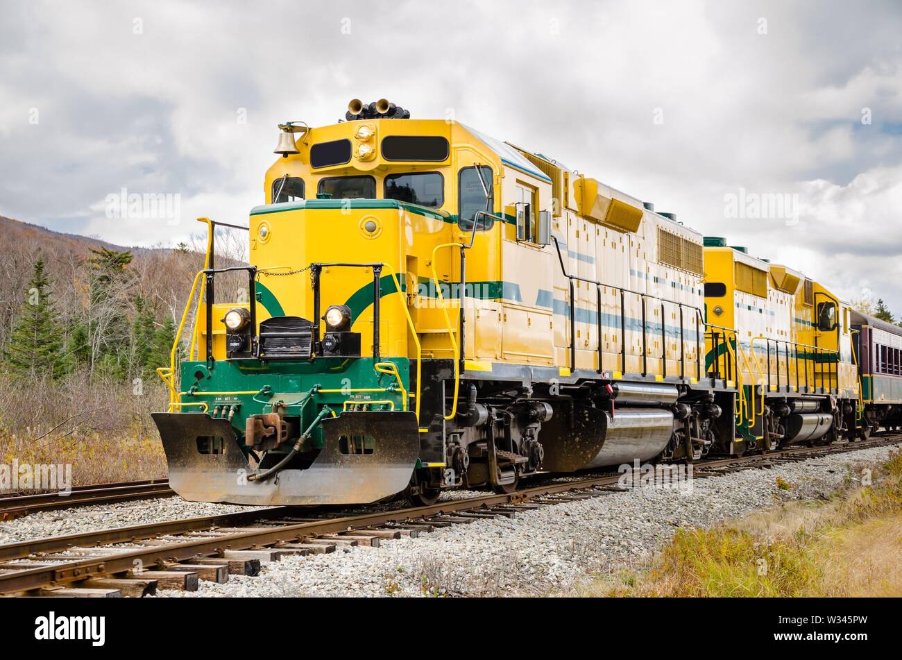 Powerful diesel locomotive pulling a passenger train on a cloudy autumn ...