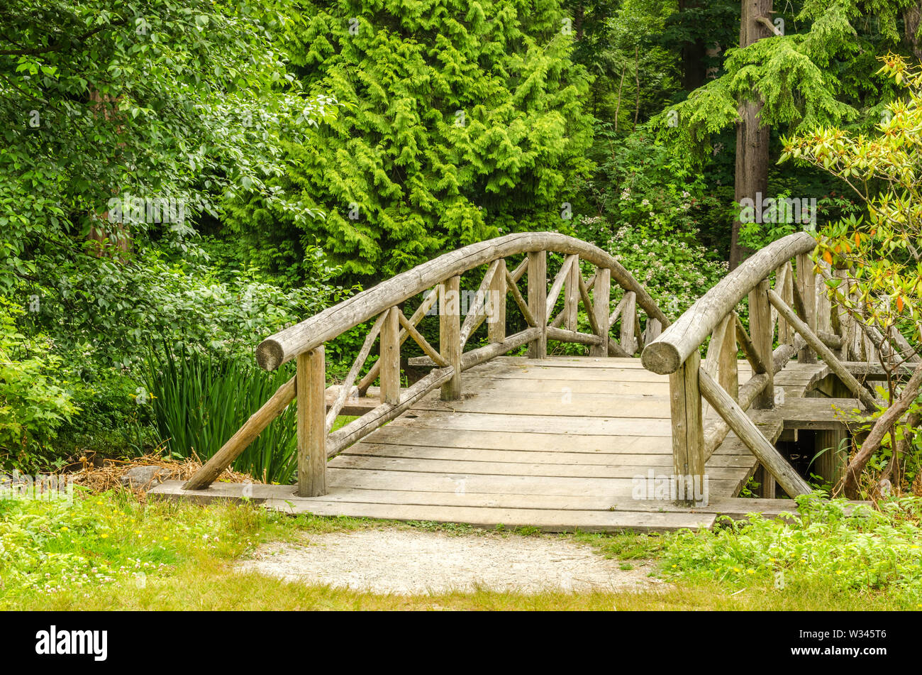 Small wooden pedestrian and bicycle bridge in a park Stock Photo - Alamy