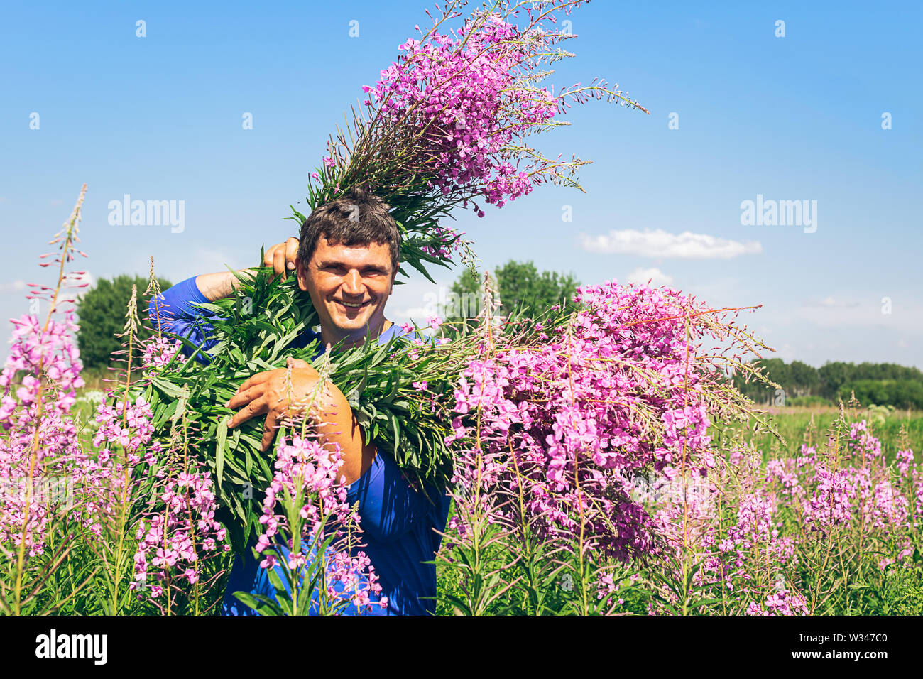 Jolly and a happy young man holding an armful of wildflowers willower ...