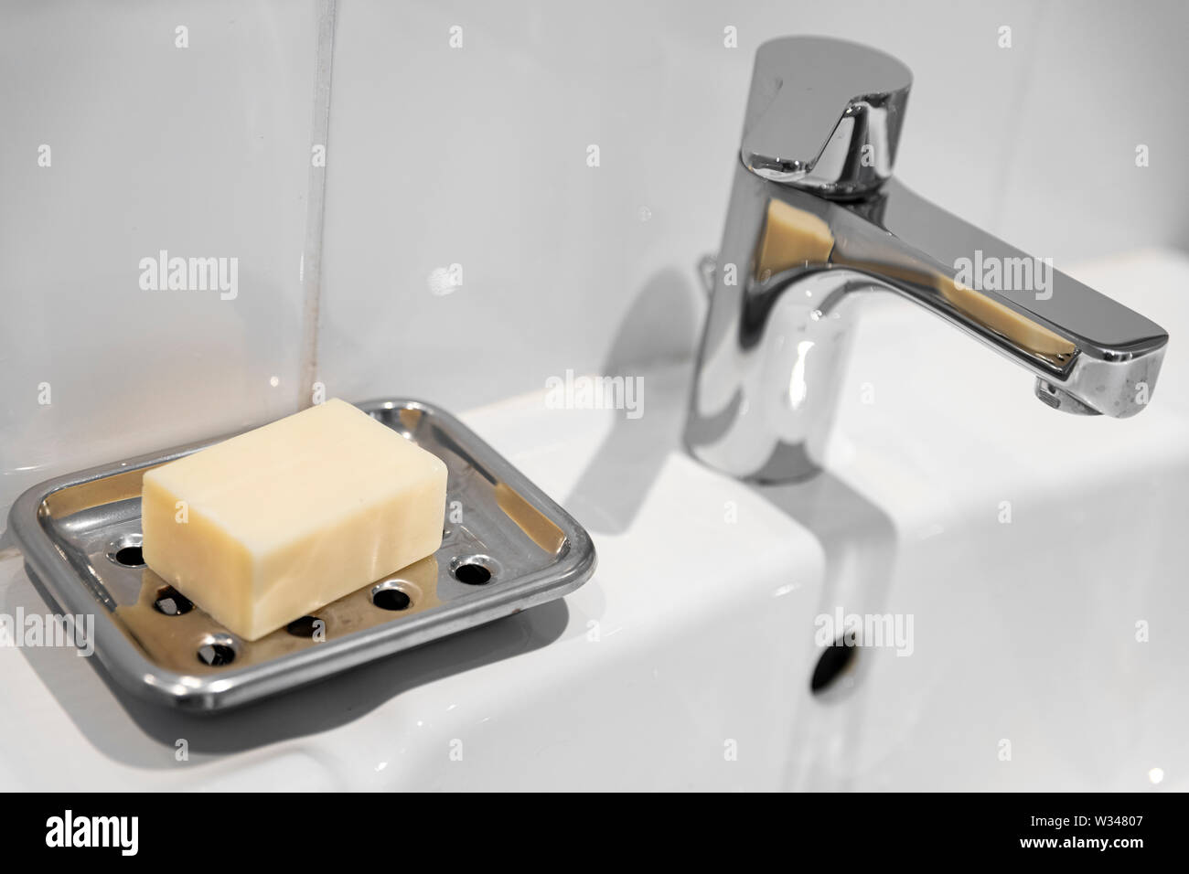 Bar of soap on a stainless steel dish on a white bathroom sink. A bar ...
