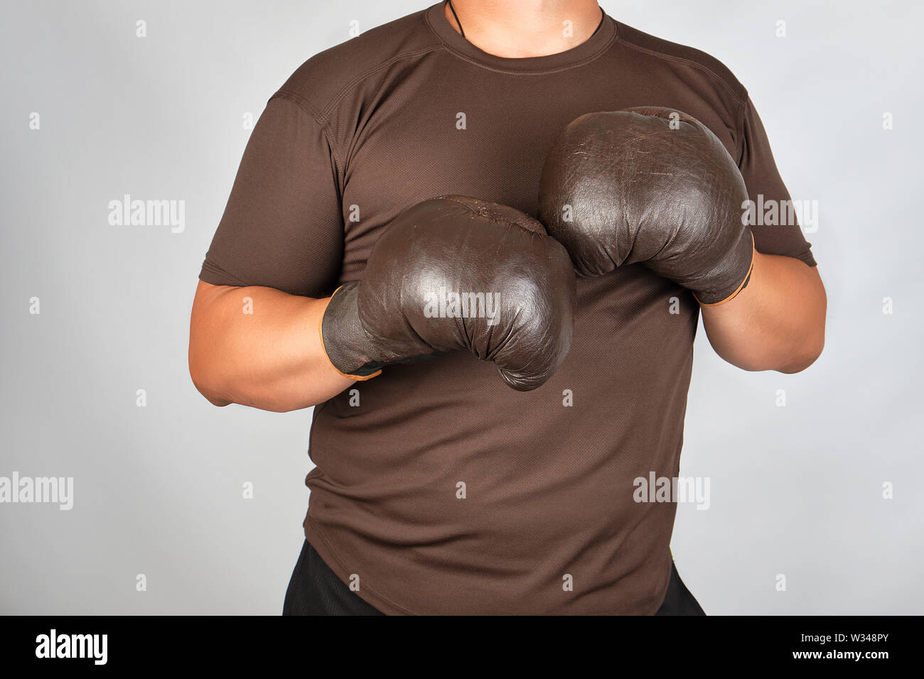 young man stands in a boxing rack, wearing very old vintage brown ...