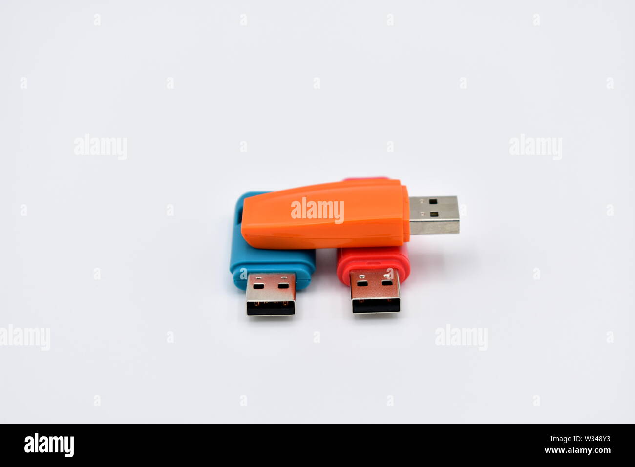 USB flash memory drives with colours, orange, blue and red, on a white ...