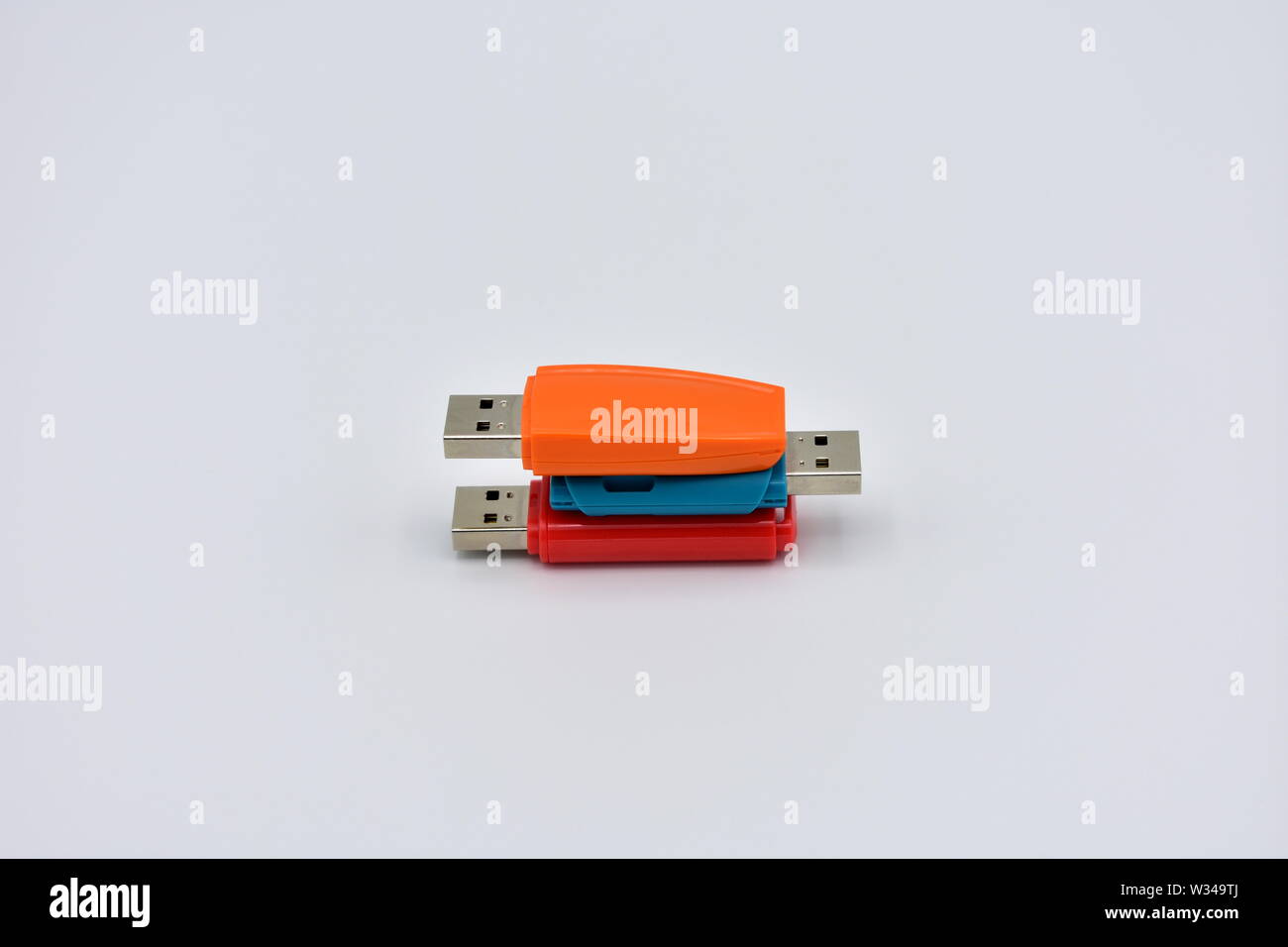 USB flash memory drives with colours, orange, blue and red, on a white ...