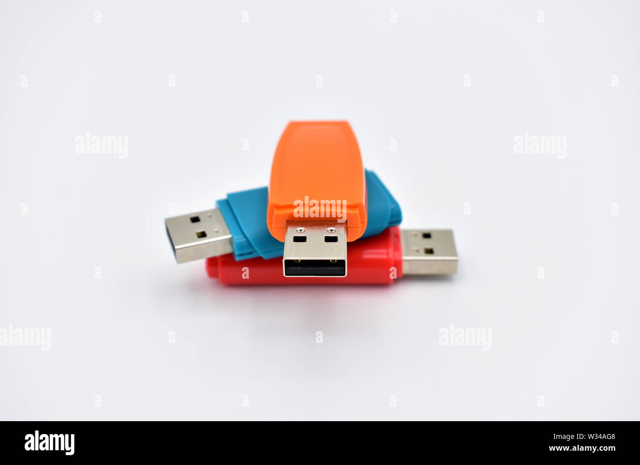 USB flash memory drives with colours, orange, blue and red, on a white ...