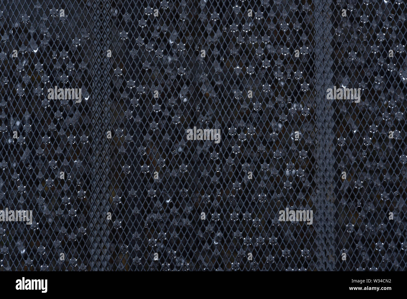 Raindrops collecting on the mesh of a garden table Stock Photo - Alamy