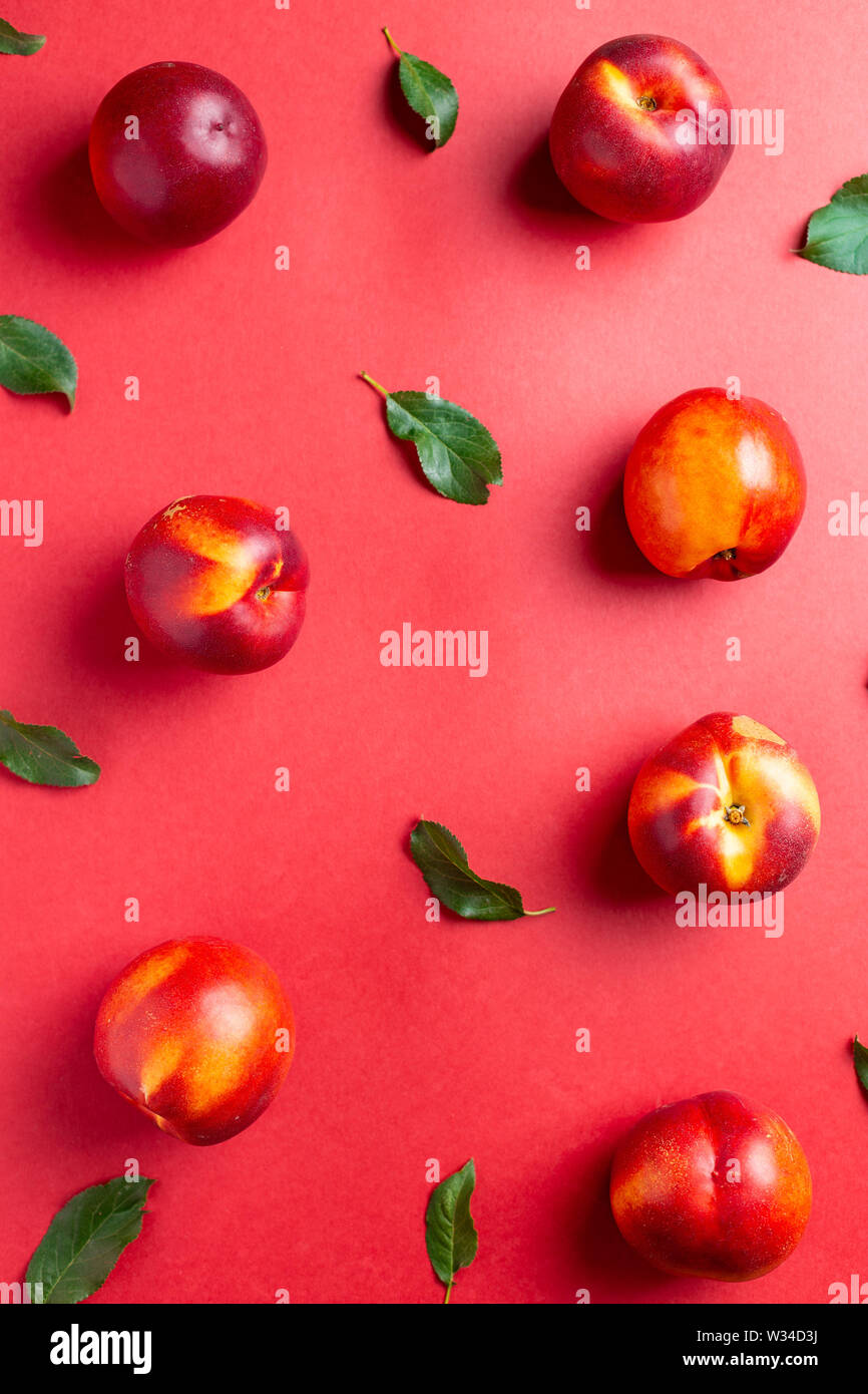 Nectarines and leaves on red background. Useful as food background ...