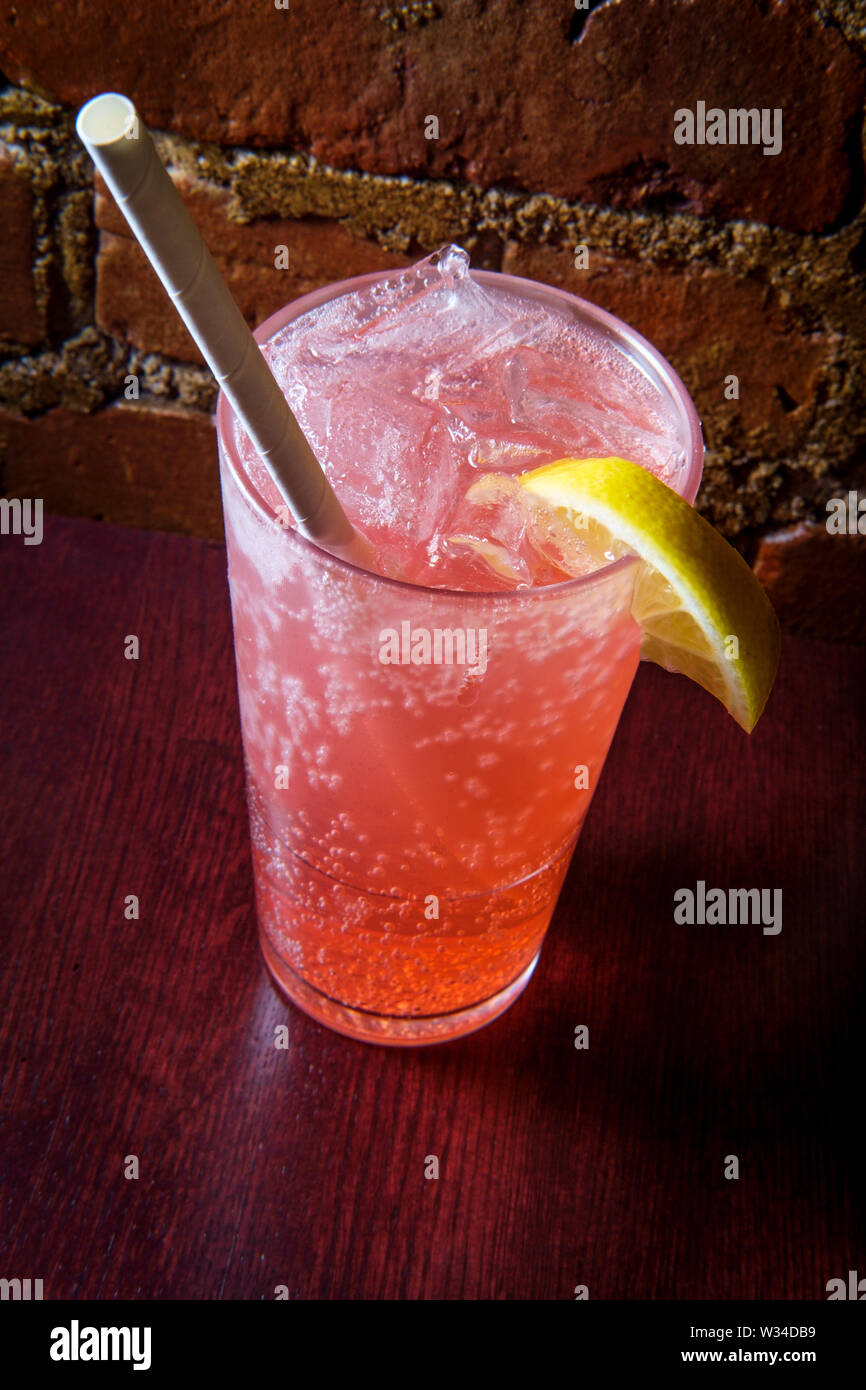 Pink Italian soda pop beverage with ice and biodegradeable paper straw ...