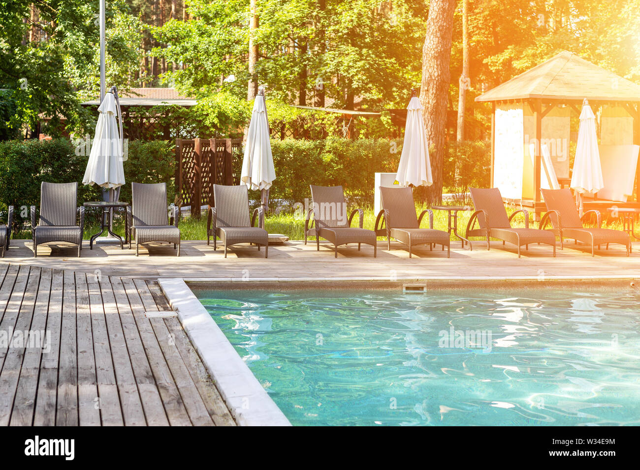 Poolside with clear blue water and loungers under umbrellas on summer ...