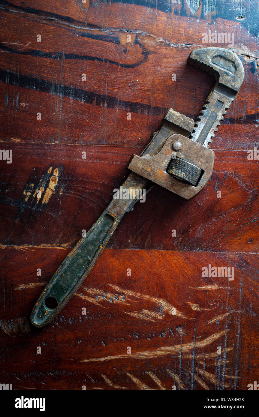 Old rusty adjustable monkey wrench contractors tool on worn wooden ...
