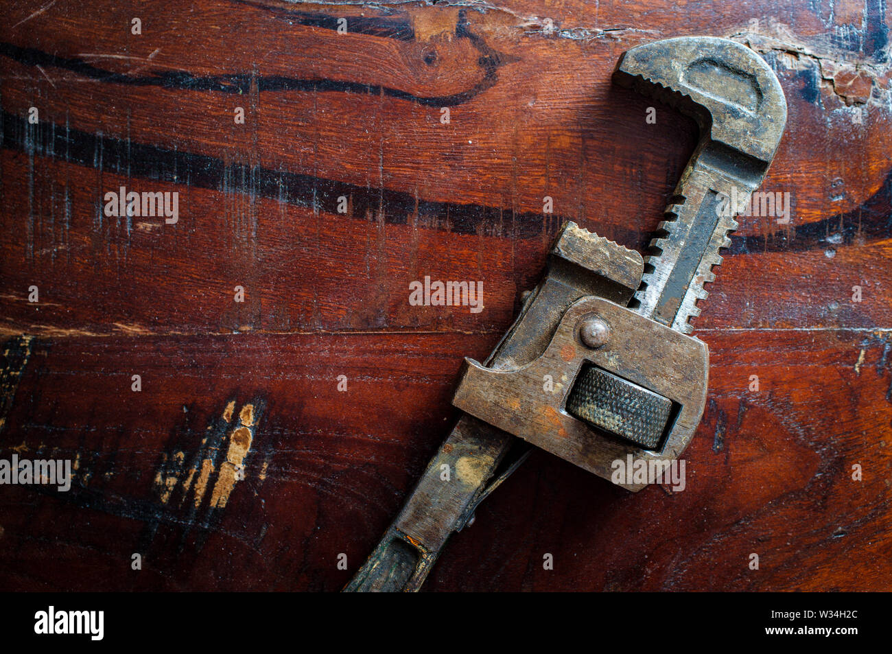 Old rusty adjustable monkey wrench contractors tool on worn wooden ...