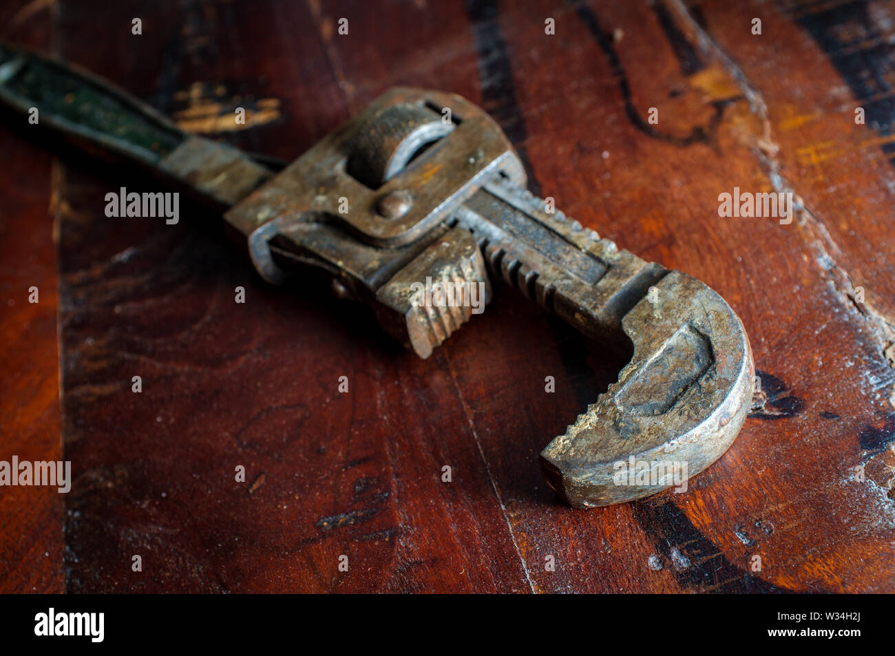 Old rusty adjustable monkey wrench contractors tool on worn wooden ...