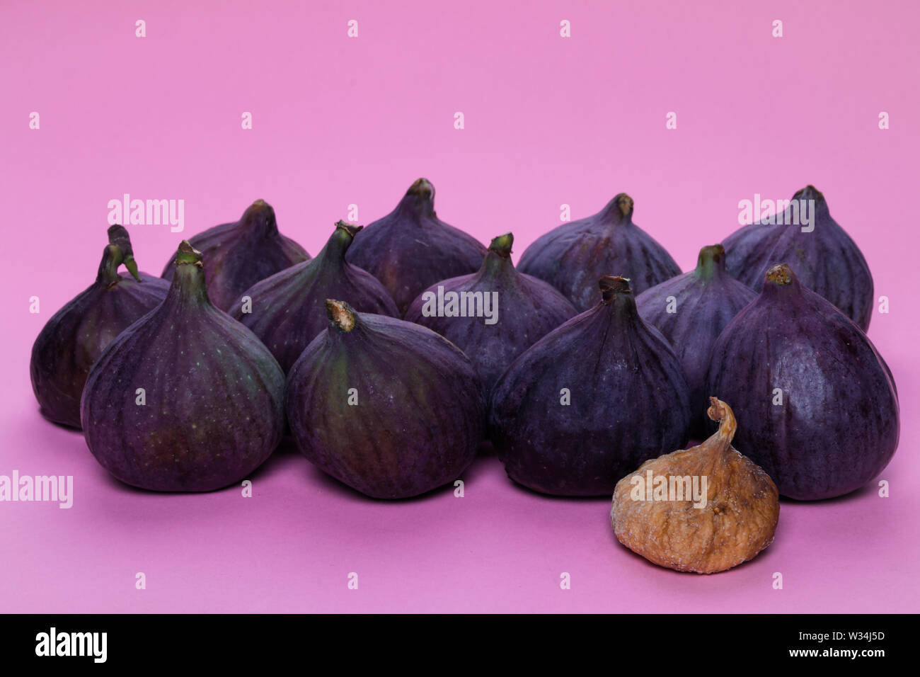 Lots of ripe, juicy, fresh, purple figs and one dried fig on a pink ...