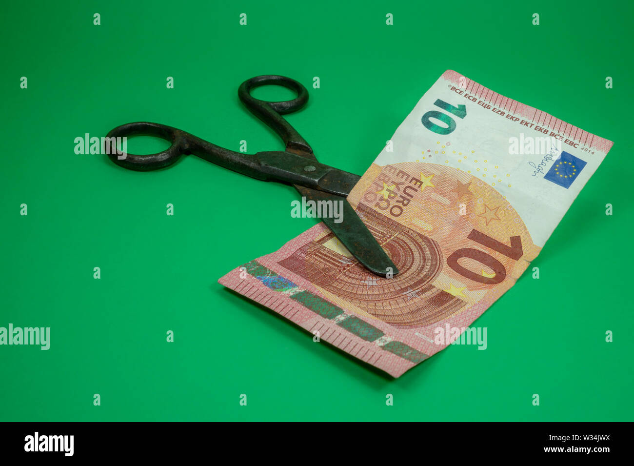 Old vintage scissors cut ten EUR banknote over green background ...