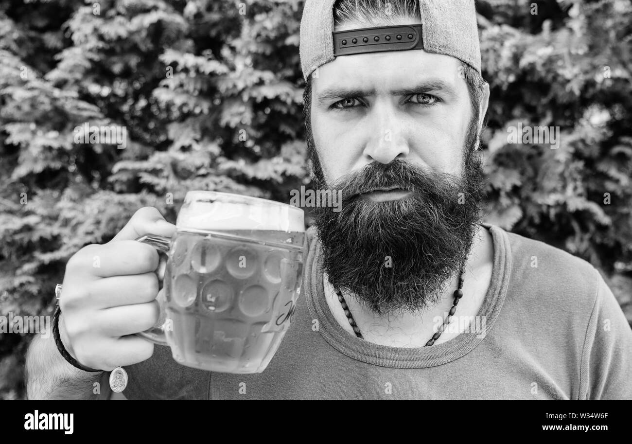 Hipster brutal bearded man hold mug cold fresh beer. Man enjoying beer ...
