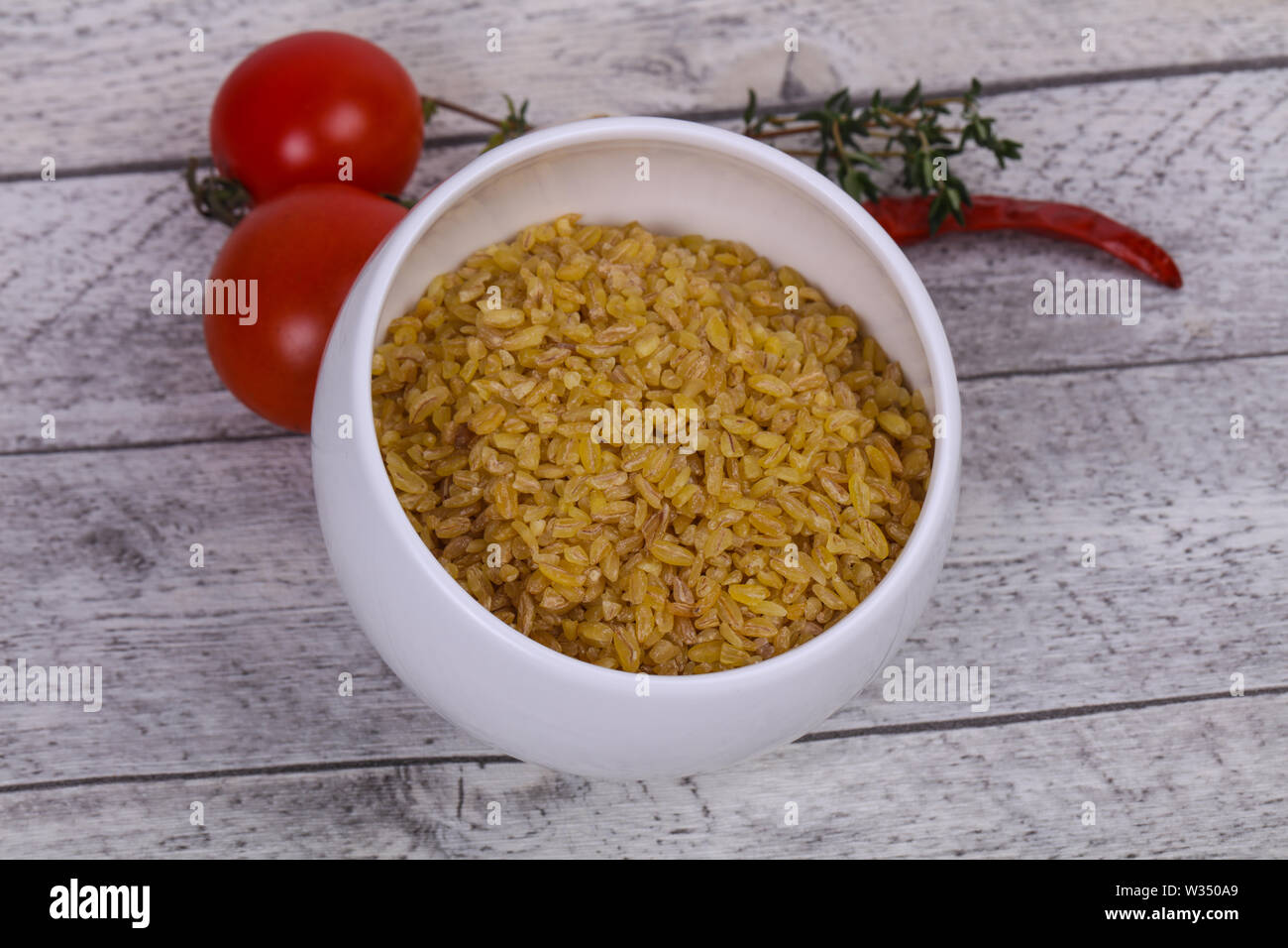 Raw golden bulgur in the bowl with tomatoes and garlic Stock Photo - Alamy