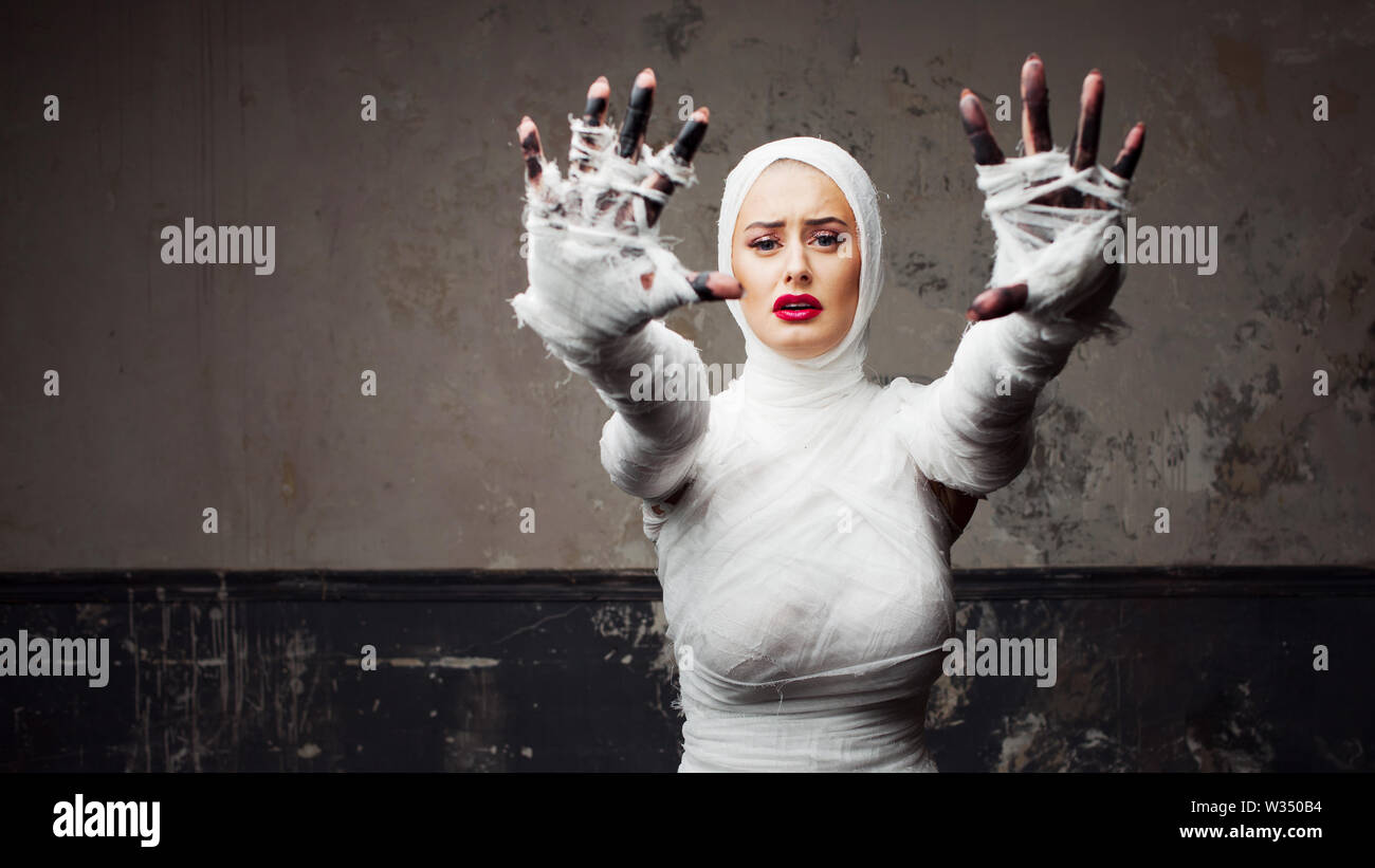 Beautiful young woman in bandages. Girl in a mummy costume, Pulling ...