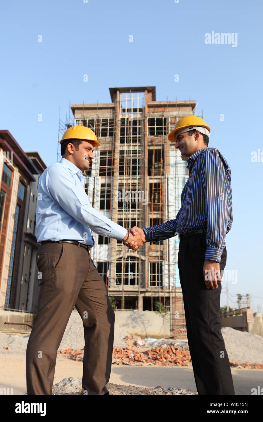Two engineers shaking hands at a construction site Stock Photo - Alamy