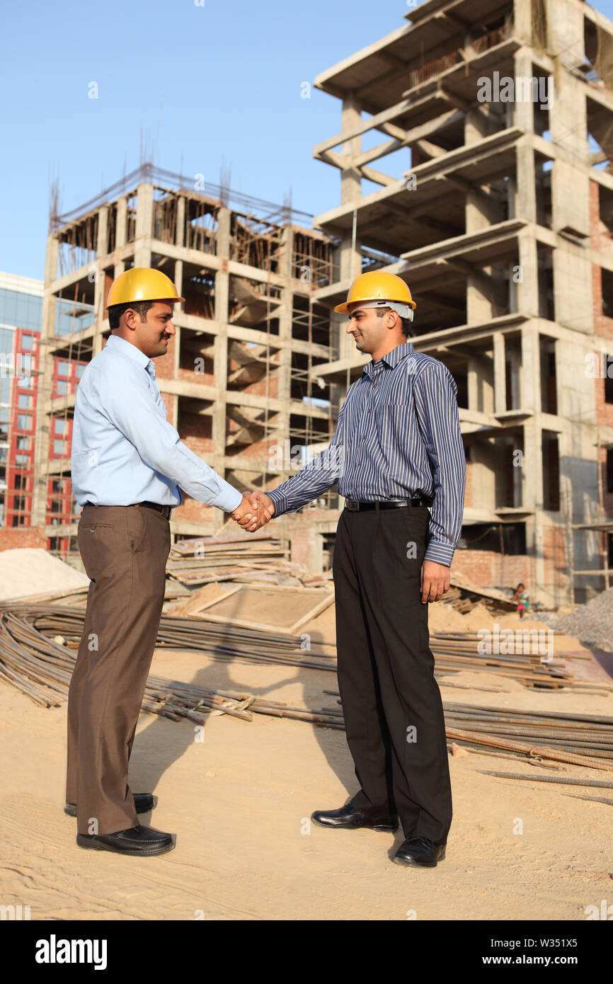 Two engineers shaking hands at a construction site Stock Photo - Alamy