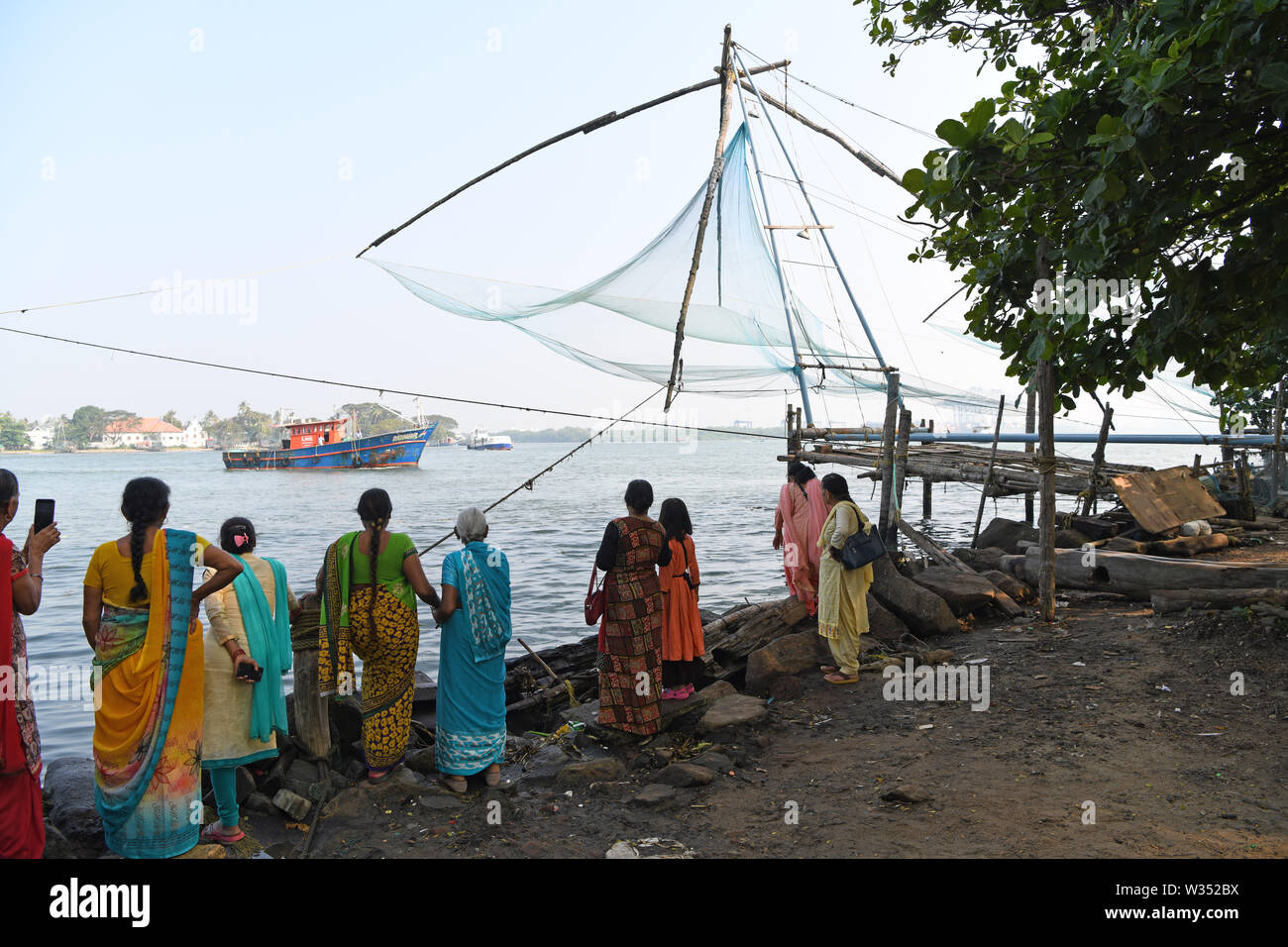 Colourful Indian ladies watching the fishing boats coming in by the ...