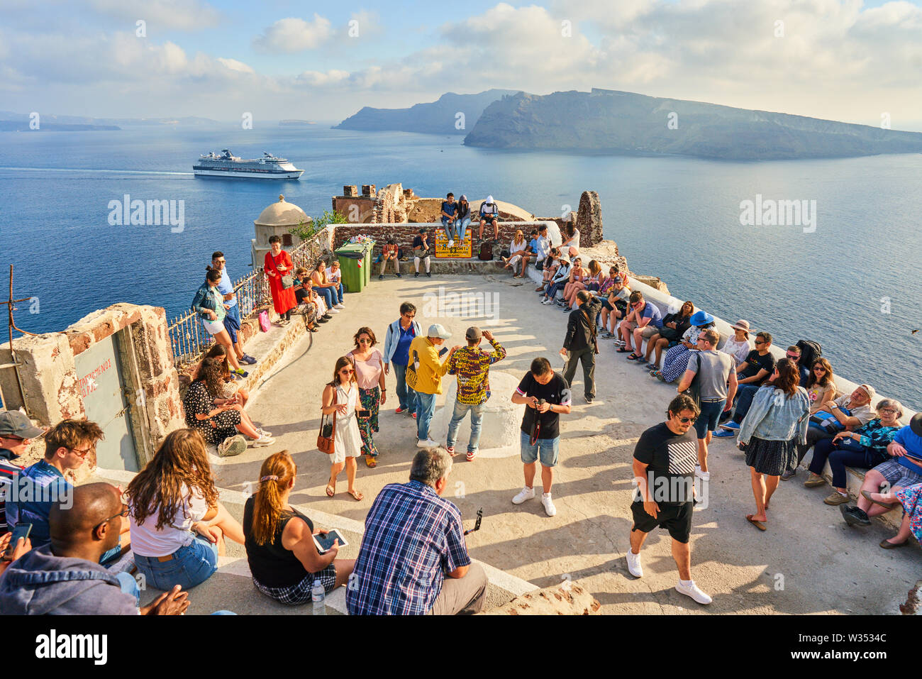 Tourists on Oia Castle wait for the sunset with Caldera View and the ...