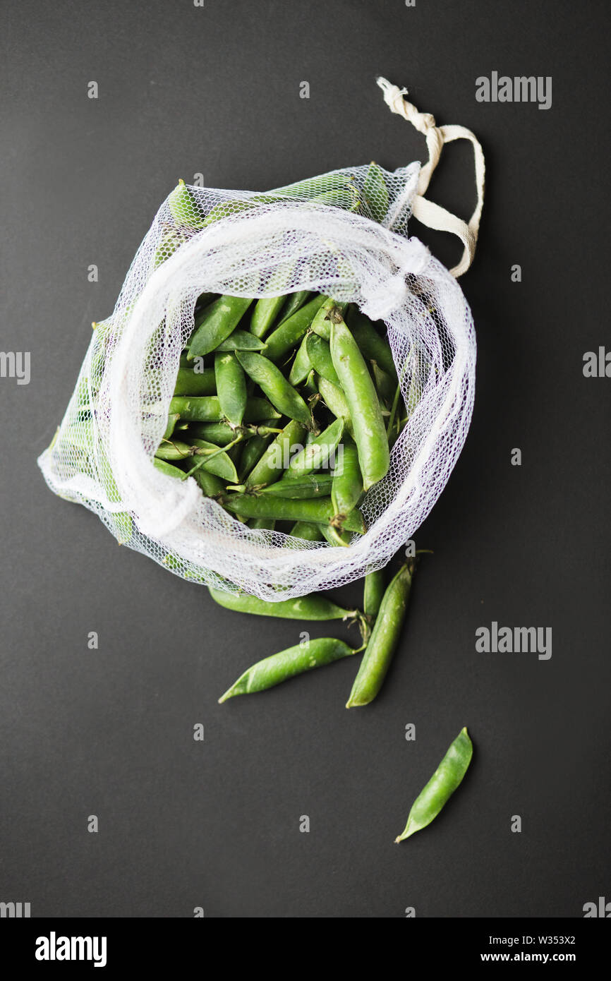 Reusable eco-friendly bag full of fresh seasonal pea pods . Taking care ...