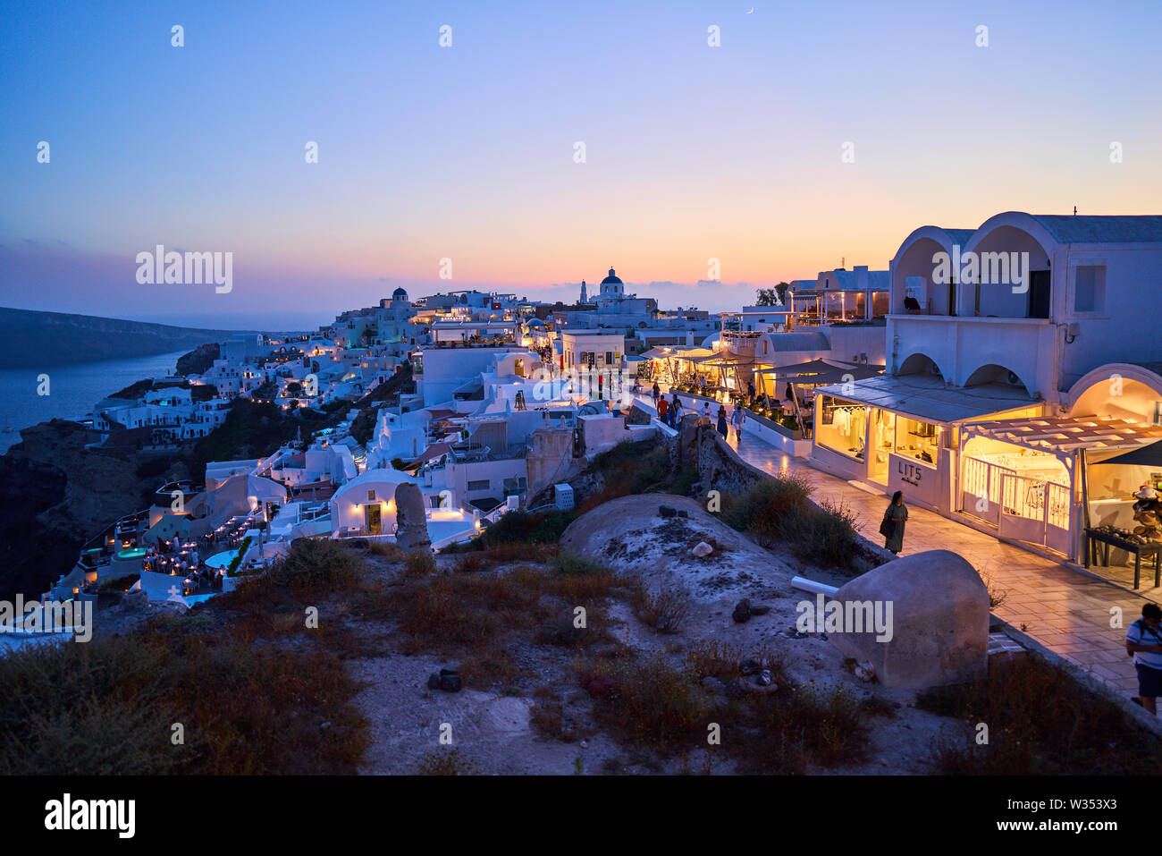 Tourists in luxury restaurants and on Oia Castle wait for the sunset ...